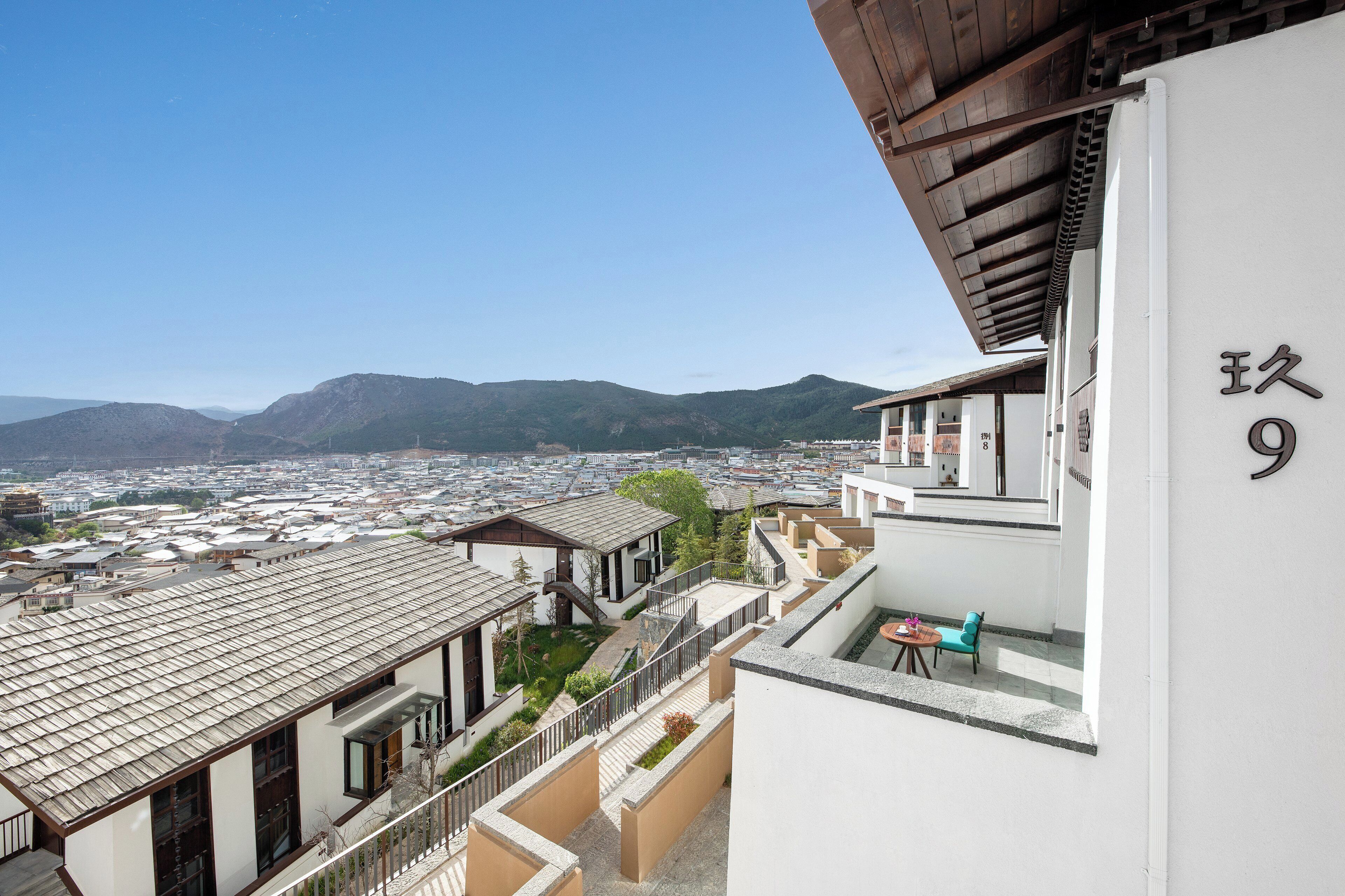 Edifício residencial com vista para a paisagem urbana e montanhas ao fundo.