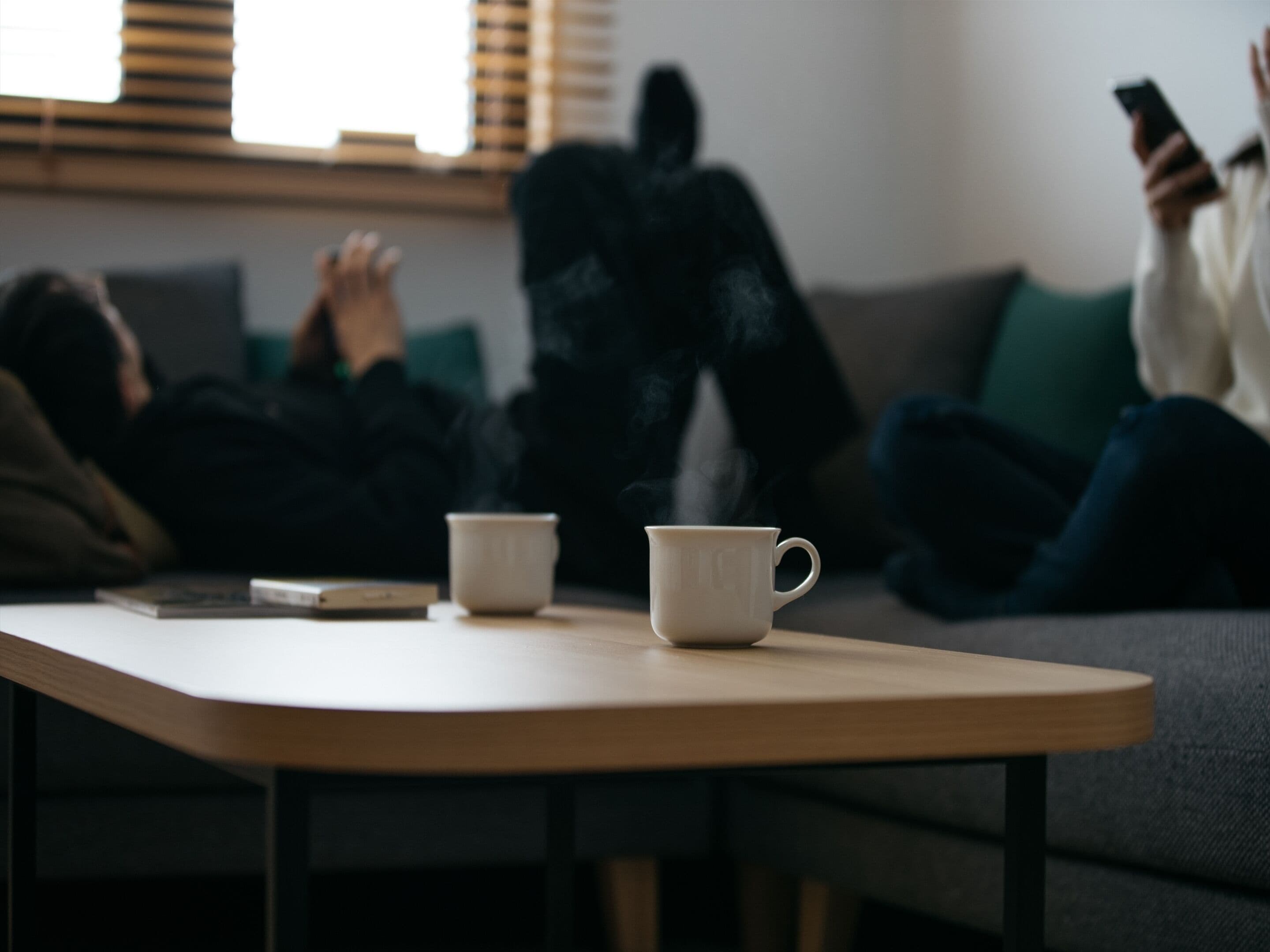 Uma sala de estar aconchegante com uma mesa de centro de madeira, uma caneca branca e um livro.