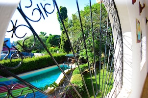Vista de uma piscina rodeada de vegetação e um edifício branco com varanda.