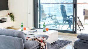 Uma sala de estar moderna com sofá, mesa de centro e vista para uma varanda com mobiliário de exterior.
