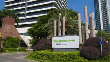 Placa para Wyndham Garden, um edifício moderno com design arquitetônico marcante, cercado por paisagismo bem cuidado e palmeiras.