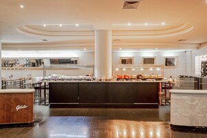 Um hall de hotel moderno com bar central, áreas de estar e um grande pilar.