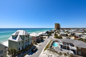 Um hotel à beira-mar com vários edifícios, uma piscina e vista para a praia e o oceano.