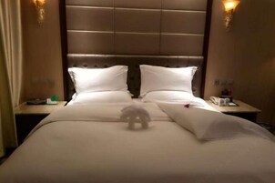 Quarto de hotel com uma cama grande, duas mesas de cabeceira e cabeceira com design acolchoado.