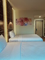 Quarto de hotel com uma cama, abajur e porta.