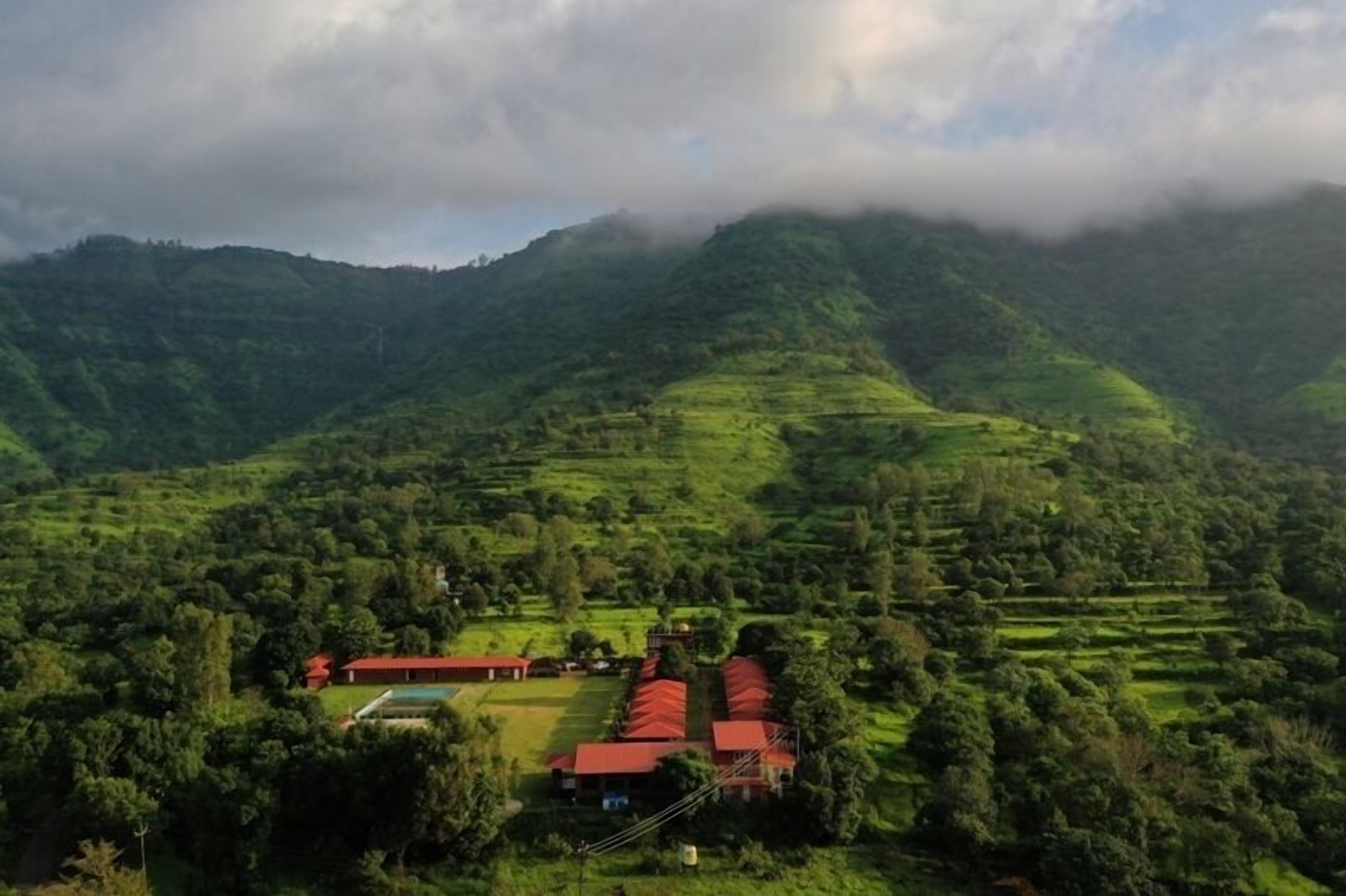 Paisagem rural com campos em socalcos e alguns edifícios com telhados vermelhos.