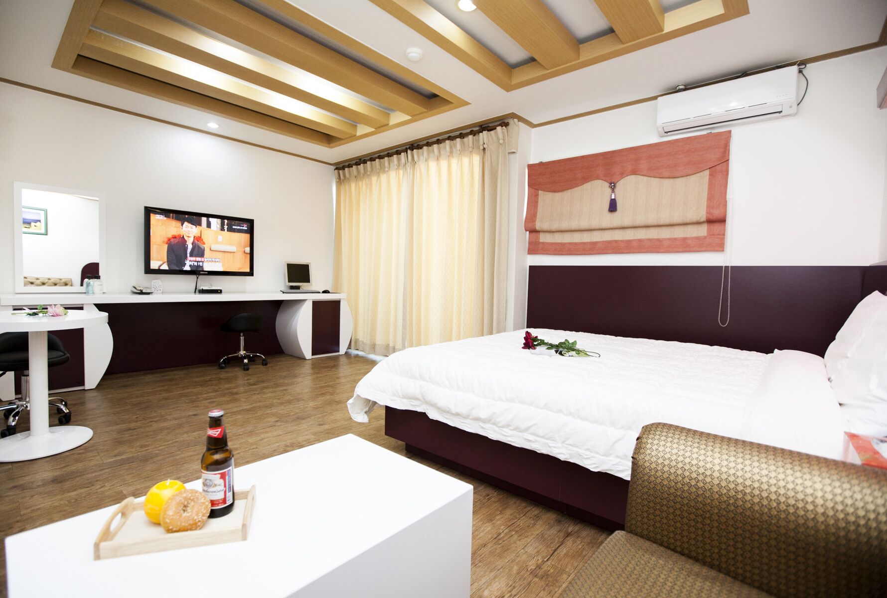 Quarto de hotel com cama, escrivaninha, cadeira, televisão e minibar.