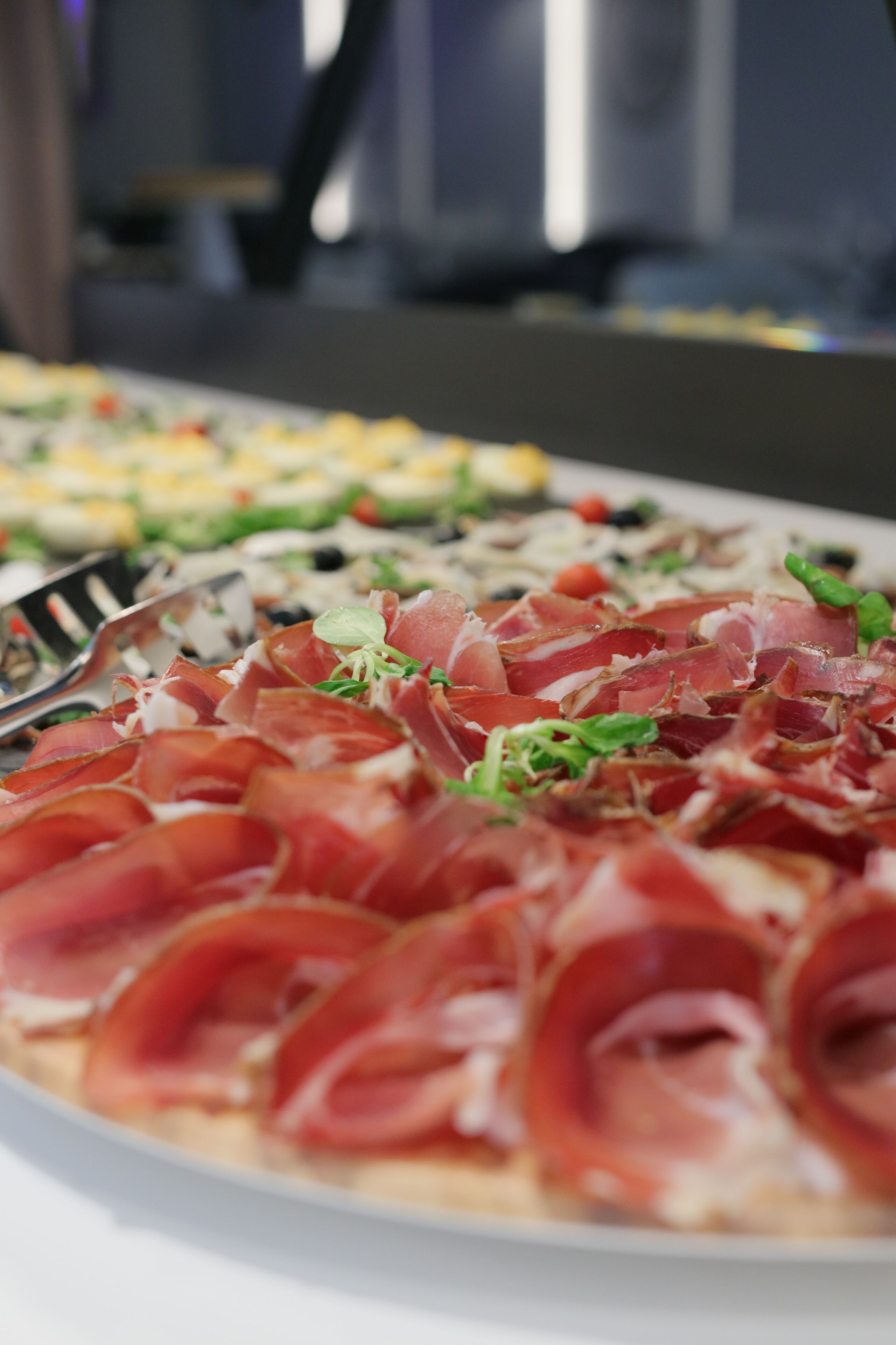 Pizza com presunto e folhas verdes.