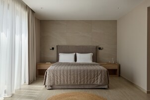 Quarto moderno com uma cama grande, mesas de cabeceira e vista para o exterior.
