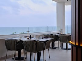 Restaurante com mesas preparadas para refeições, vista para o mar.