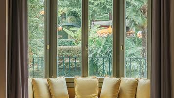 Sofá de canto com vista para um jardim exuberante através de grandes janelas.