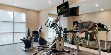 Uma academia com diversos equipamentos de exercício, incluindo esteira, elíptico e bicicleta ergométrica.