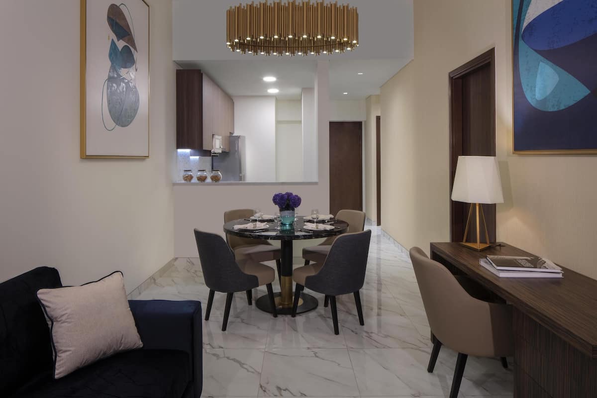 Uma sala de jantar moderna com uma mesa redonda, cadeiras e um candelabro.