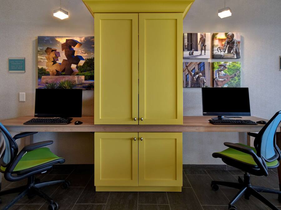 Um espaço de trabalho com duas mesas, duas cadeiras e um armário amarelo.