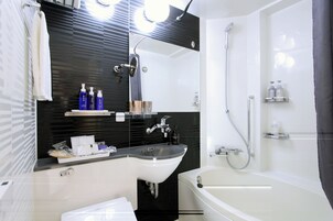 Casa de banho moderna com lavatório branco, banheira e chuveiro. Há produtos de higiene no lavatório e uma toalha pendurada na parede.