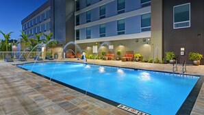 Hotel com piscina, área de estar externa e placa indicando limite de profundidade de 1,5 metros.