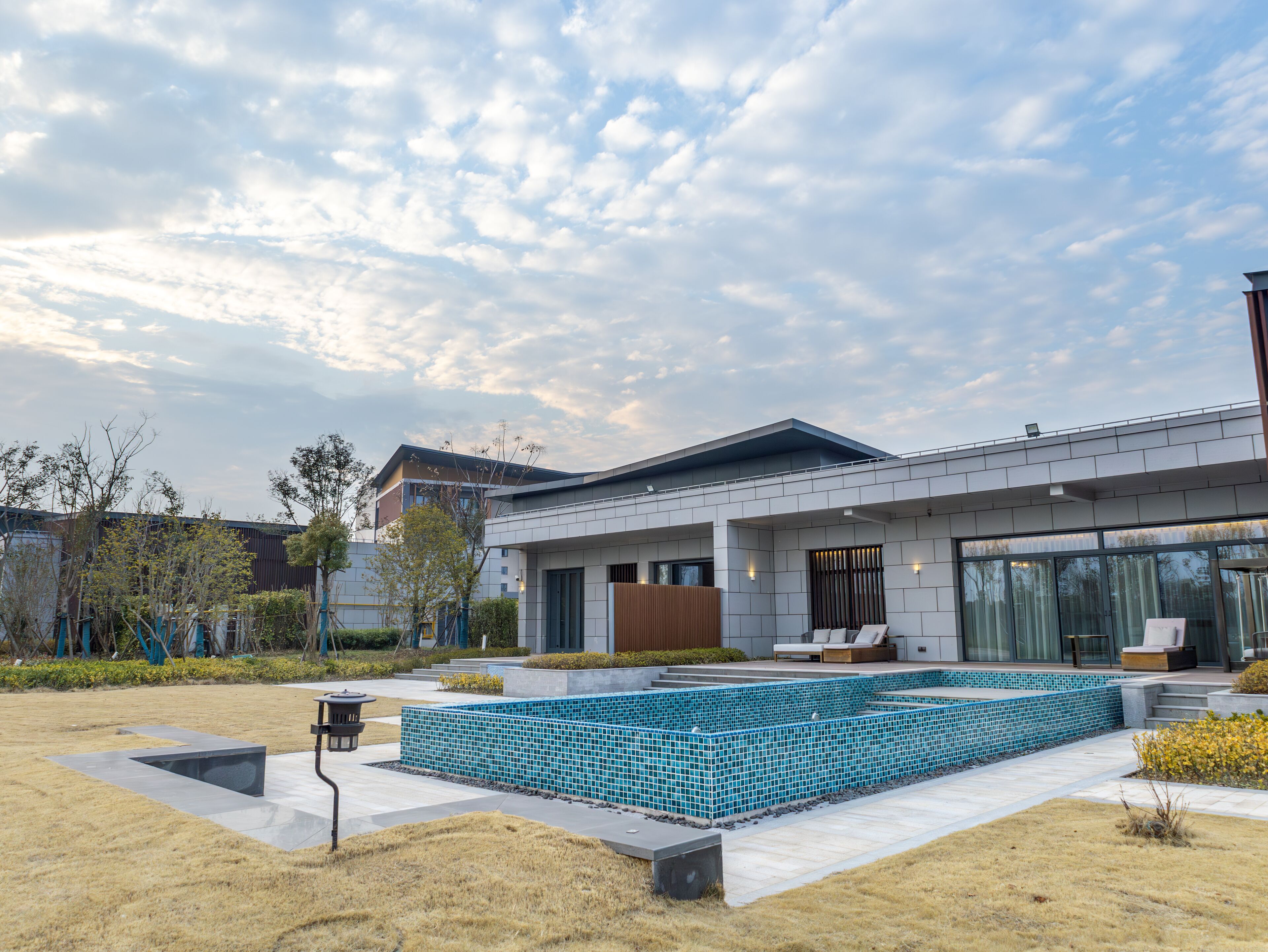 Uma casa moderna com piscina, um terraço com móveis de exterior e uma grande porta de vidro.