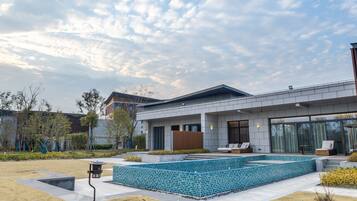 Uma casa moderna com piscina, um terraço com móveis de exterior e uma grande porta de vidro.