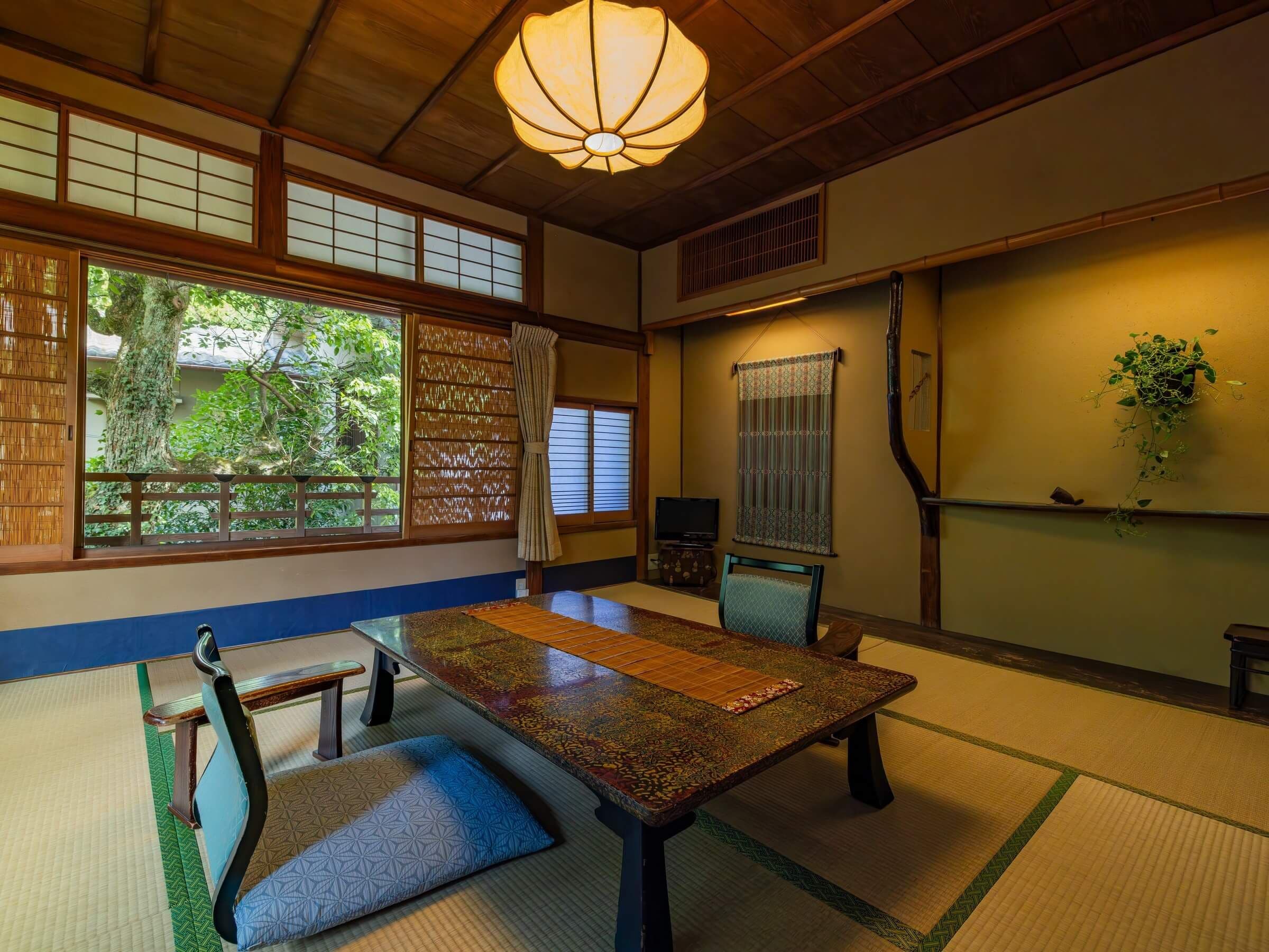 Um quarto japonês tradicional com tatames, uma mesa baixa e um candeeiro pendente.