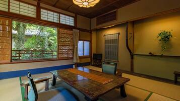 Um quarto japonês tradicional com tatames, uma mesa baixa e um candeeiro pendente.