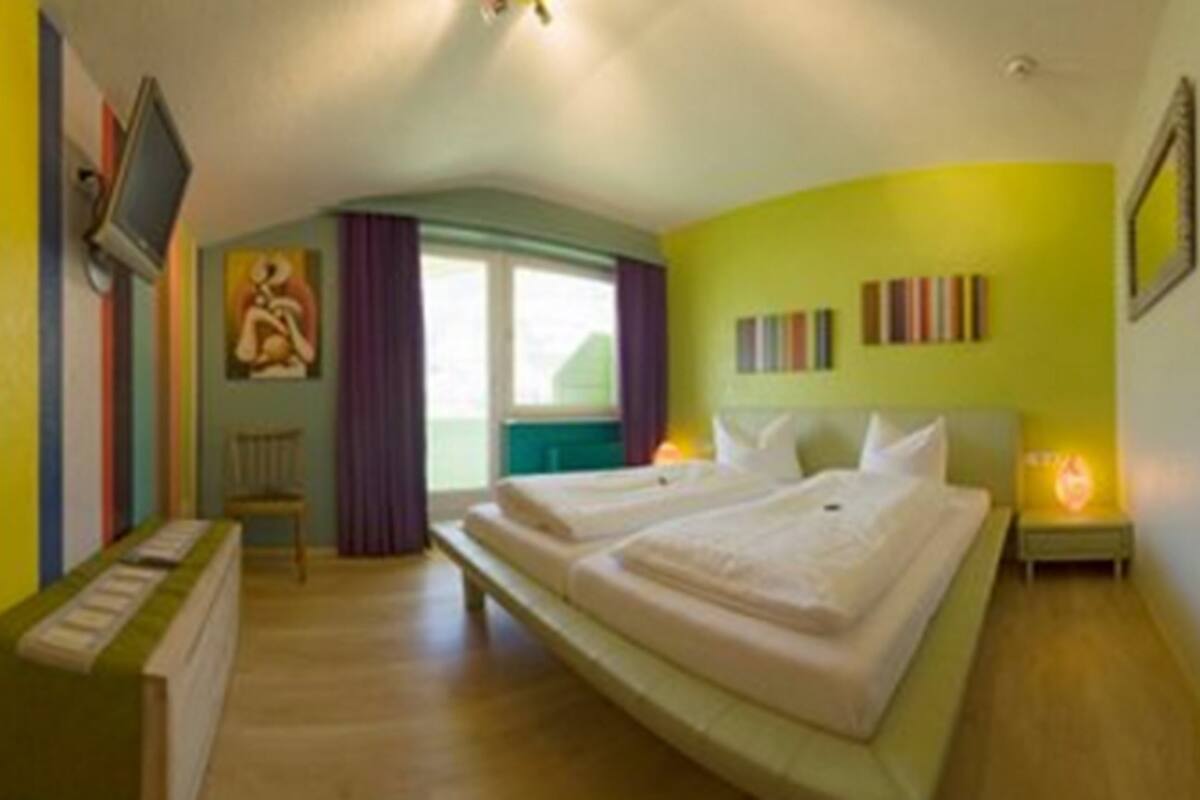 Quarto de hotel com duas camas, uma escrivaninha e uma cadeira.