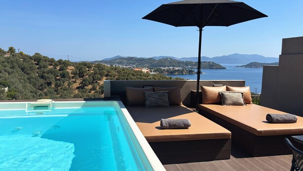 Área de piscina no terraço, com vista para o mar e colinas.
