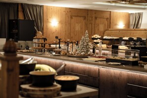 Disposição de buffet com diversos alimentos e um pinheiro decorativo de Natal.