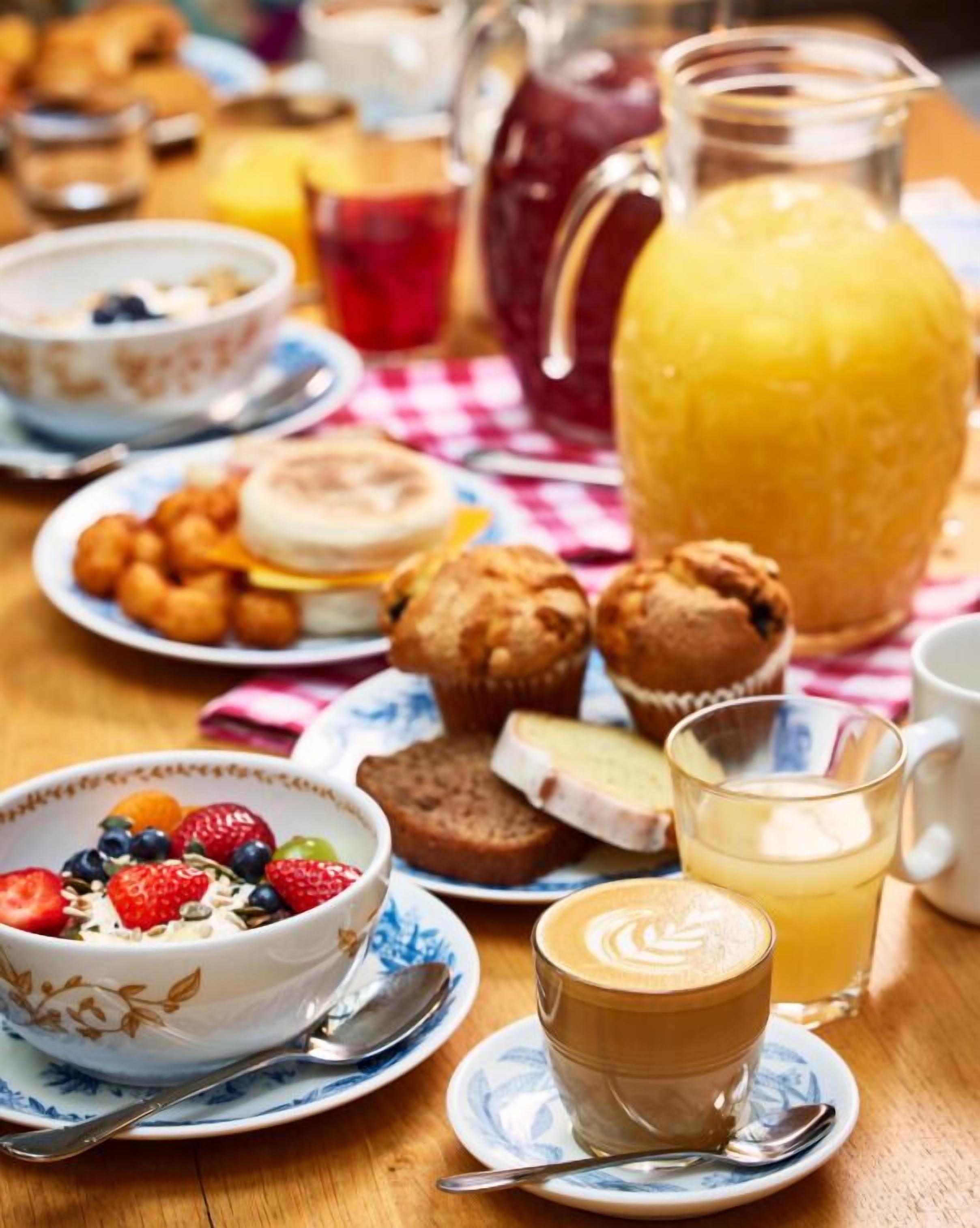 Uma mesa de café da manhã com diversos alimentos, um jarro e uma xícara de café.