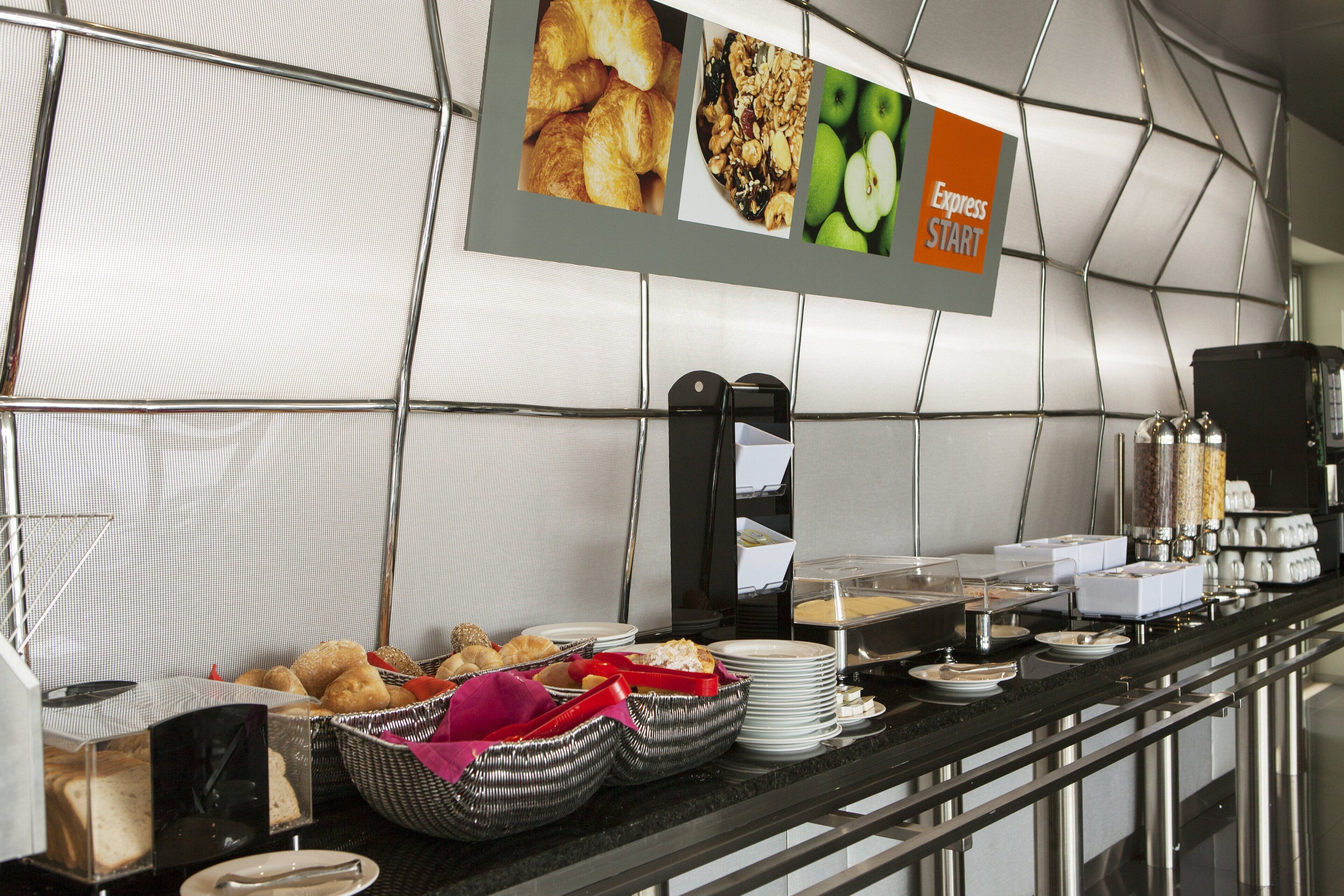 Disposição de buffet com diversos alimentos, incluindo pão, doces e uma placa indicando 'Express Start'.