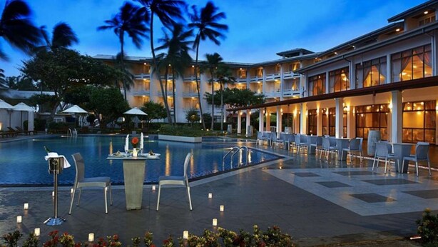 Um hotel com piscina, área de estar ao ar livre e palmeiras.