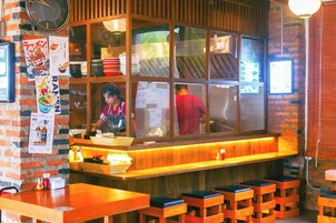 Um restaurante com parede de tijolos, balcão de madeira e banquetas.