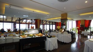 Uma área de buffet com diversos alimentos e mesas dispostas para refeições.