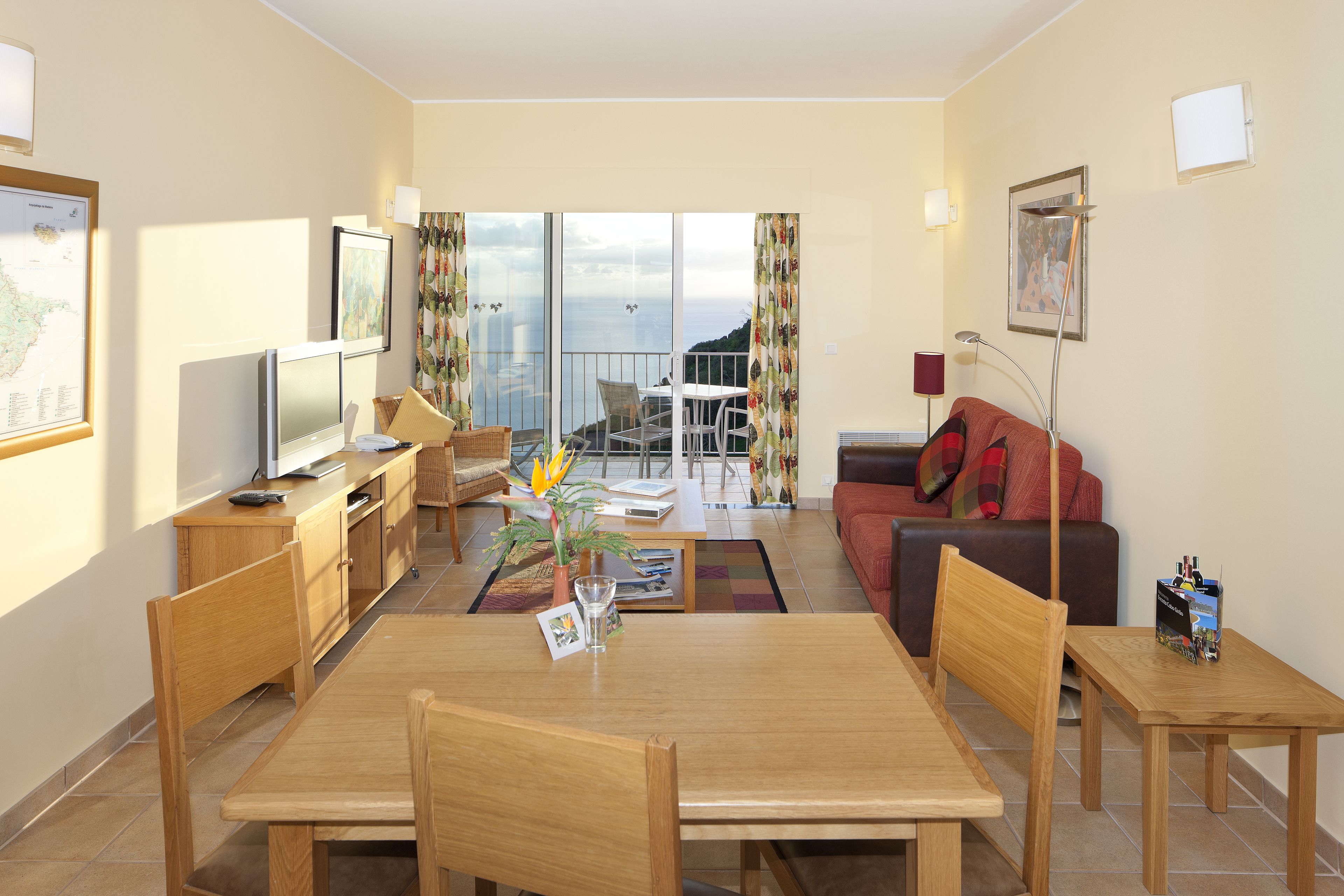 Uma sala de estar moderna com área de jantar, televisão e varanda com vista.