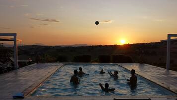 Piscina com pessoas aproveitando a vista do pôr do sol.