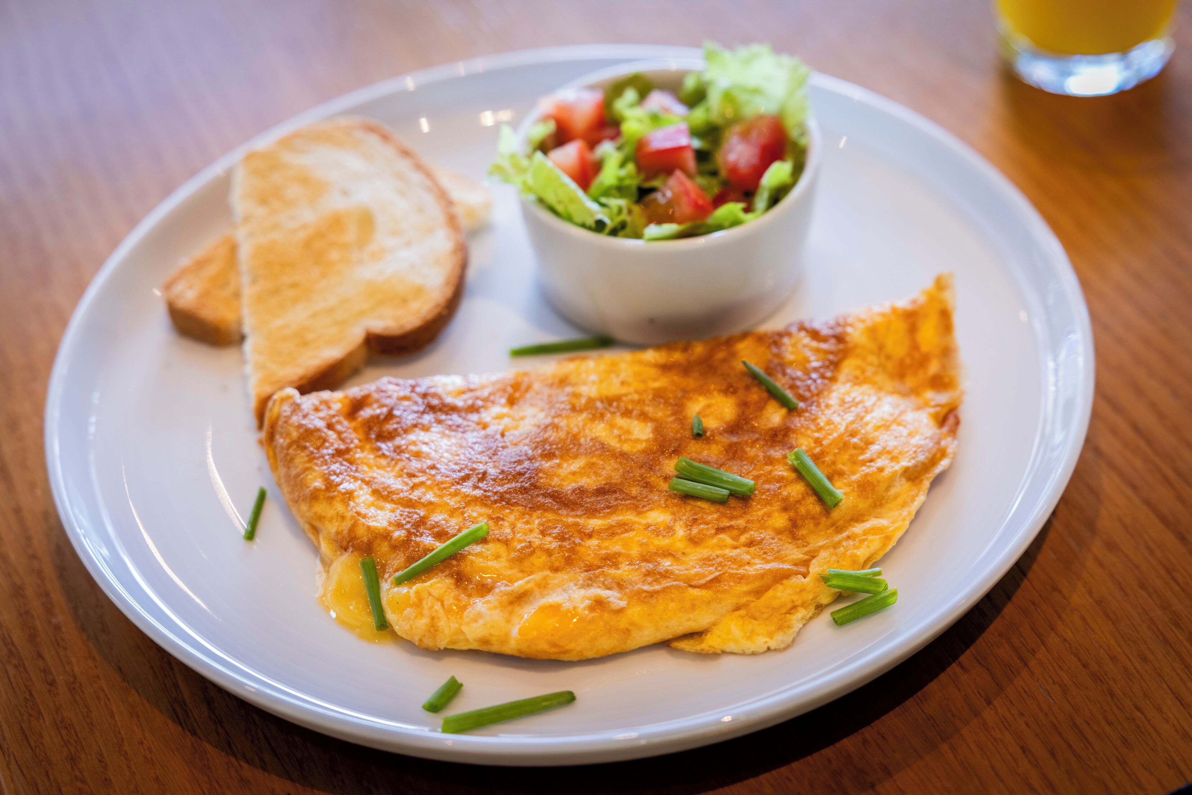 Um prato com omelete, torradas e uma salada pequena.
