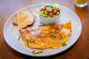 Um prato com omelete, torradas e uma salada pequena.
