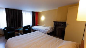 Quarto de hotel com duas camas, lareira, uma mesinha e duas cadeiras.