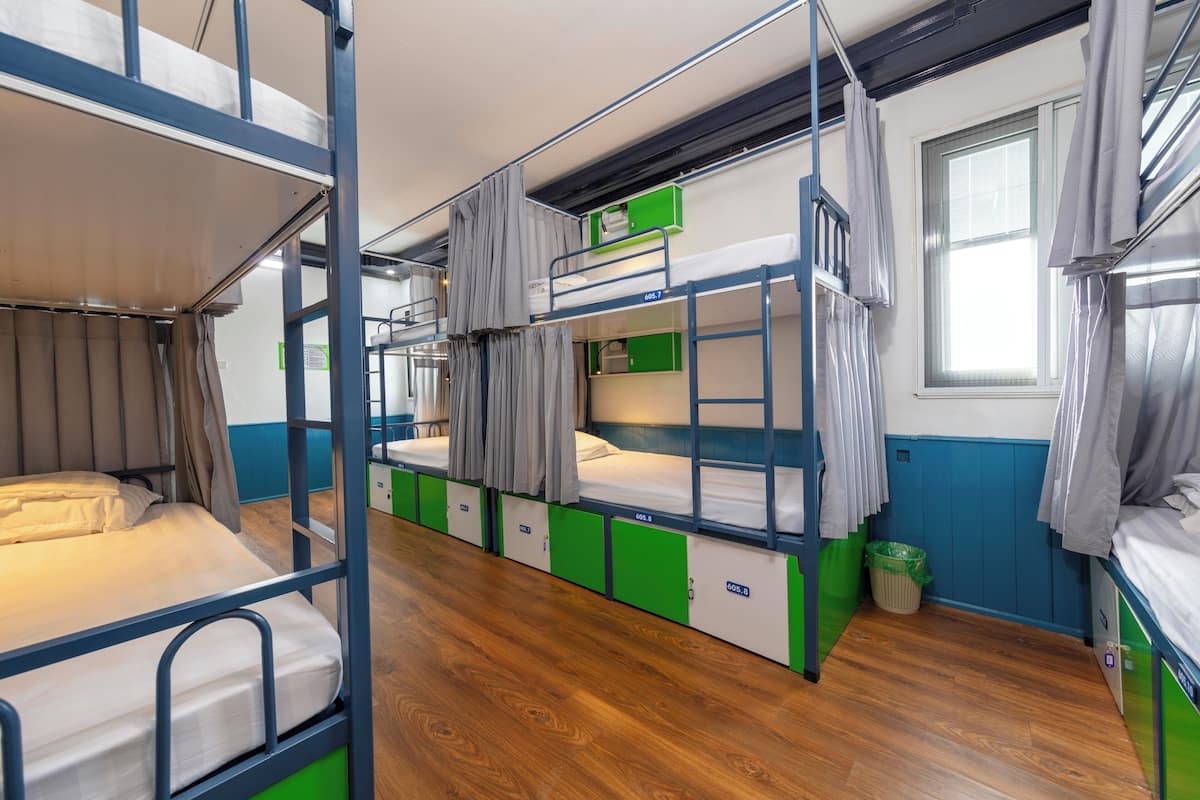 Quarto de dormitório com beliches, janela e lixeira.