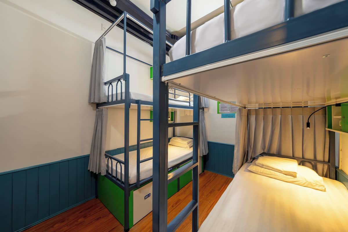 Quarto com beliche, piso de madeira e parede verde.