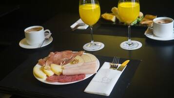 Uma mesa de café da manhã com um prato de comida, dois copos de suco de laranja, uma xícara de café e um cardápio.