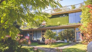 Um edifício moderno com jardim no telhado verde, janelas amplas e um gramado bem cuidado.