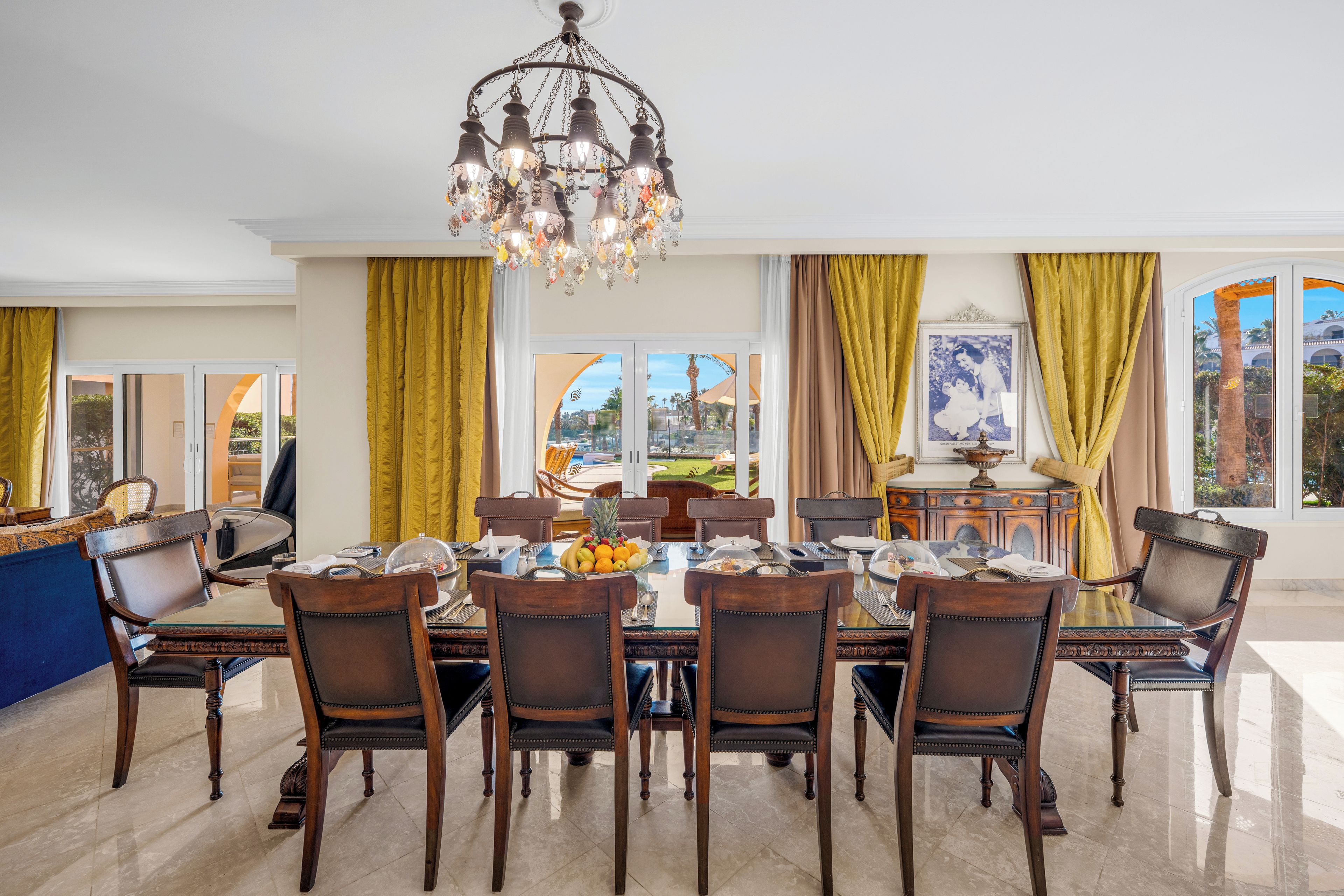 Uma sala de jantar com uma mesa grande, cadeiras e um candelabro.