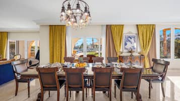 Uma sala de jantar com uma mesa grande, cadeiras e um candelabro.