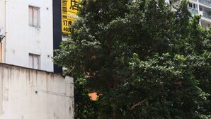 Um edifício com vários andares e varandas, com um grande letreiro amarelo com caracteres chineses.