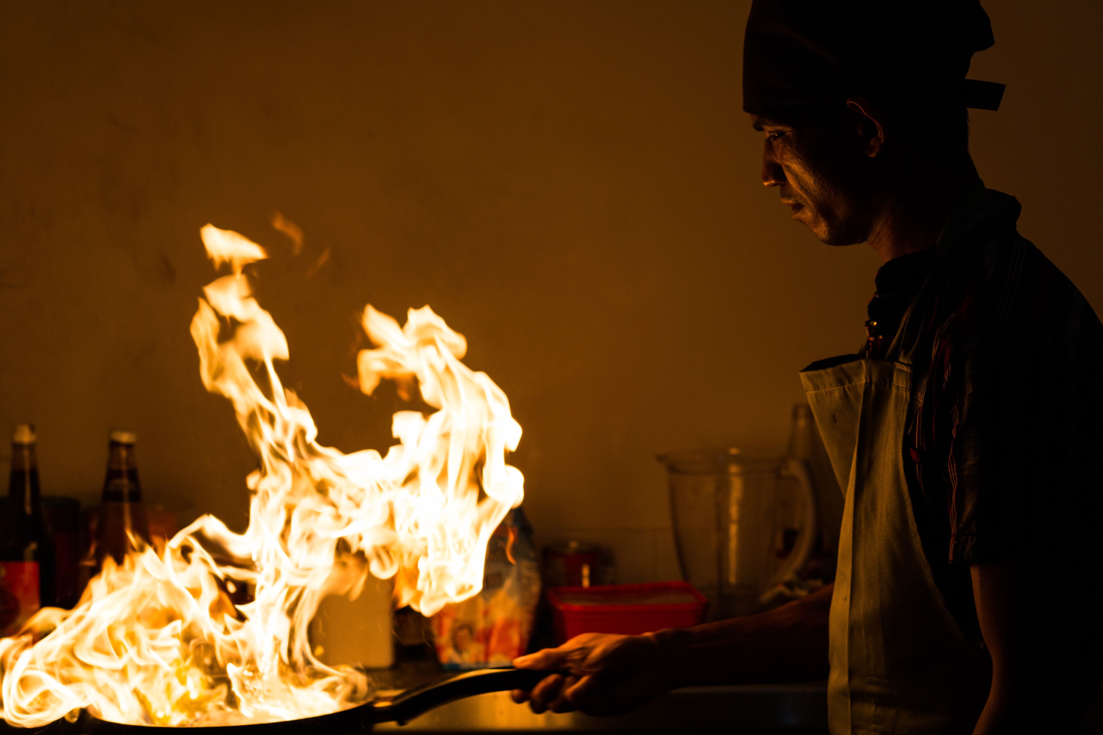 Alguém cozinhando com chamas em uma panela.