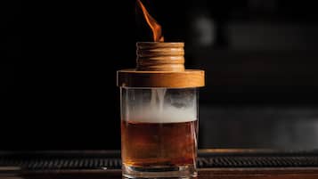 Um copo com tampa de madeira e uma chama visível, indicando uma bebida quente.