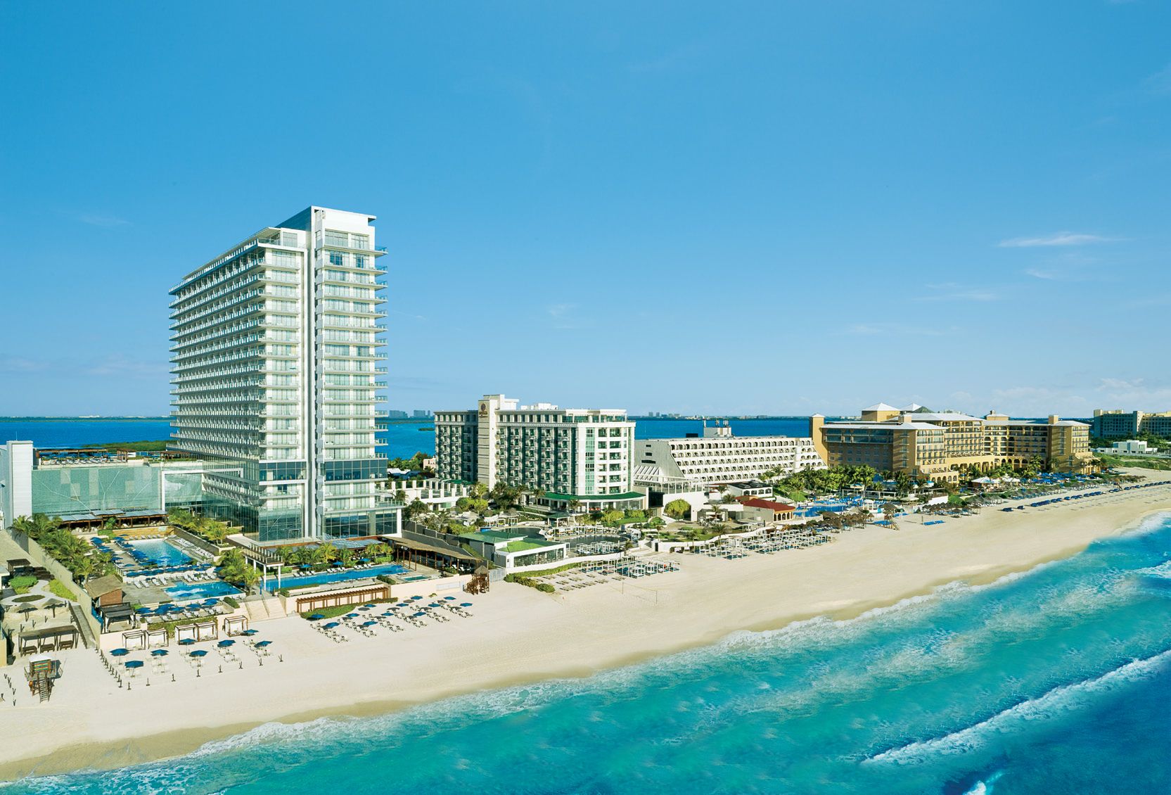 Um hotel à beira-mar com vários edifícios, acesso direto à praia e área de piscina.