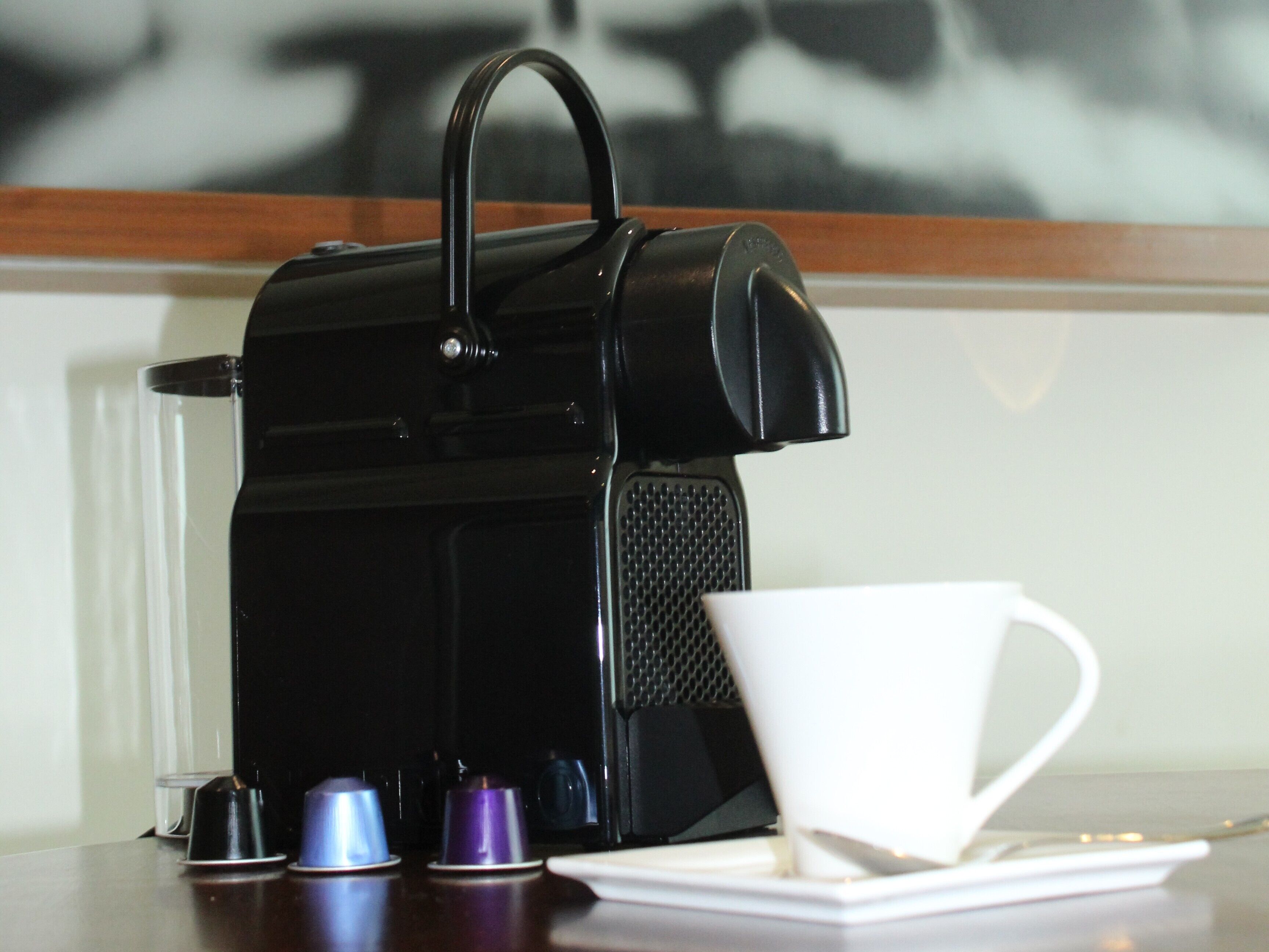 Uma cafeteira com uma xícara e pires sobre uma mesa.