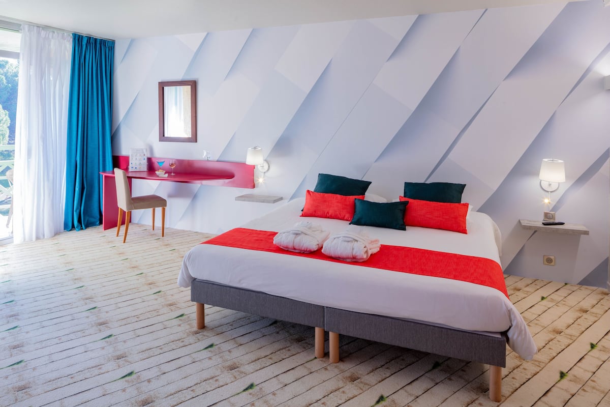 Quarto de hotel moderno com cama, escrivaninha e cadeira.