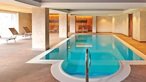 Piscina interna com espreguiçadeiras e área de spa.
